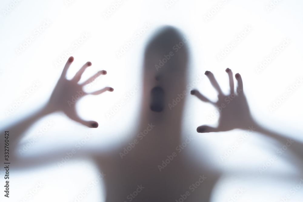 Blurred silhouette shadow of a terrorific body shape behind a white ...