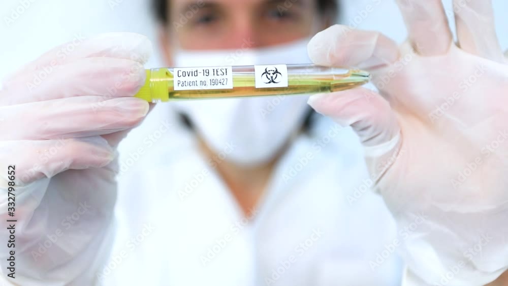 Selective focus closeup liquid filled vial labeled Covid-19 test being ...