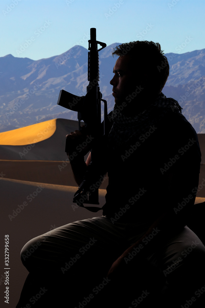 Silhouette of a male soldier resting in the shade on a desert and ...