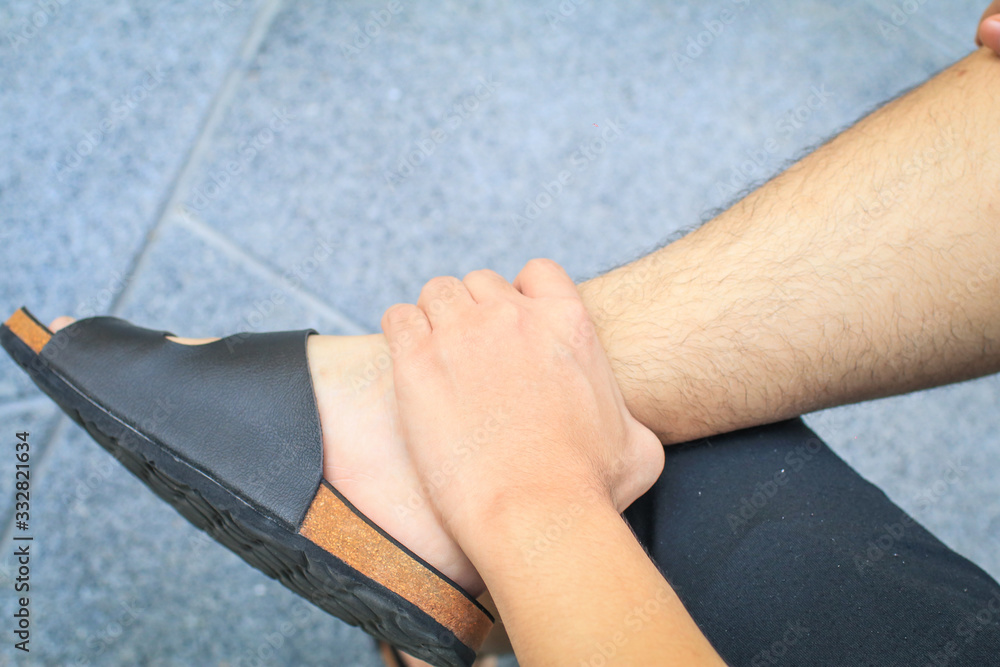 The man holds his hands to the ankle, the pain in his leg,The concept ...