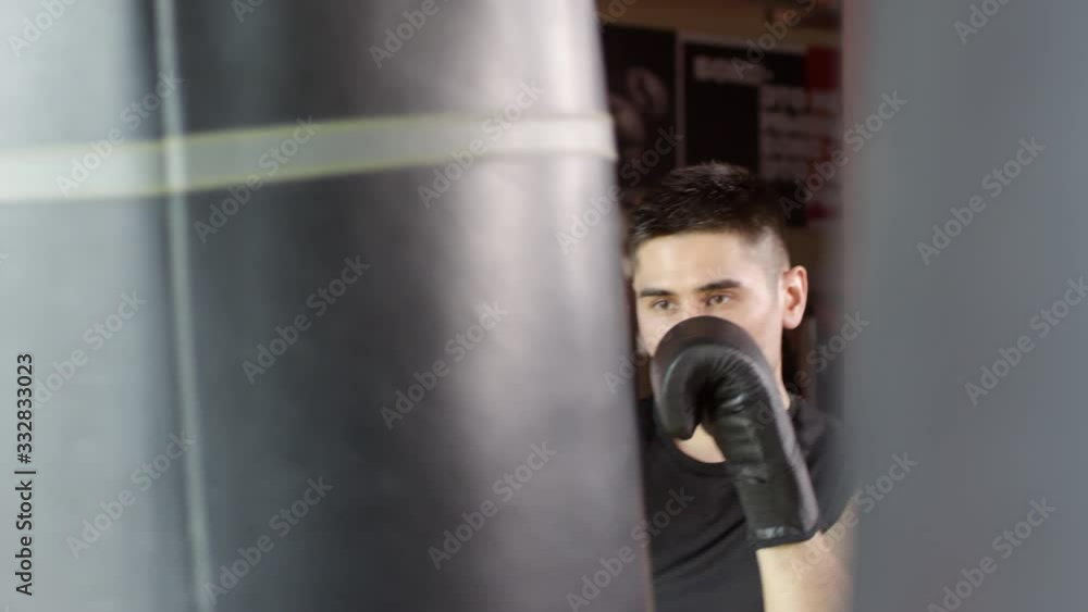 Handheld camera shot of professional male boxer in gloves hitting heavy ...