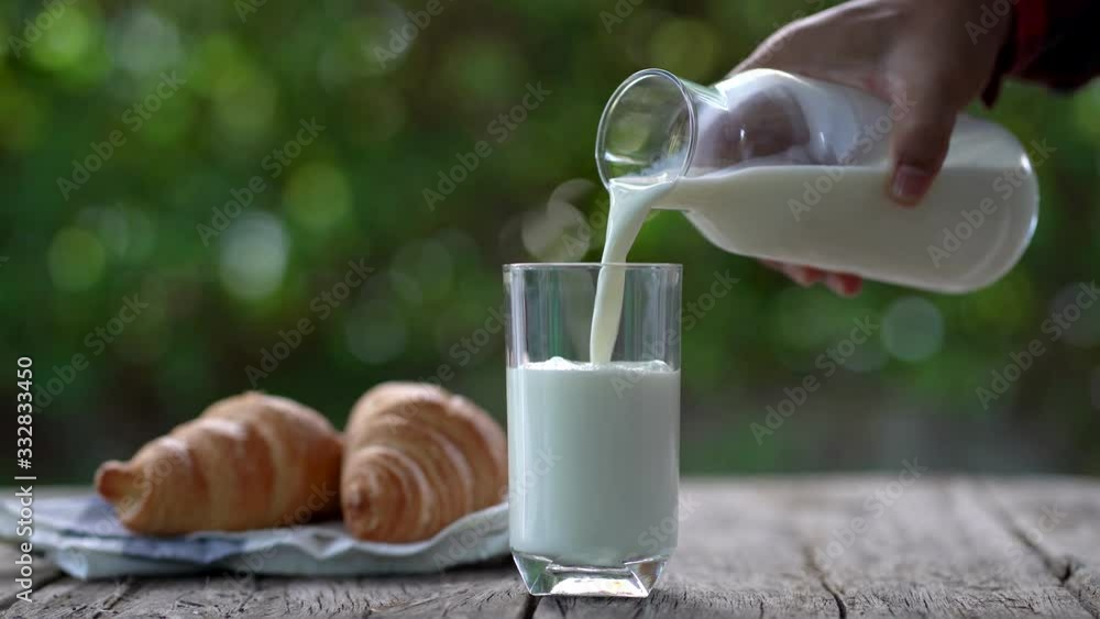 A sunny day in the garden pour milk in a transparent cup where milk ...