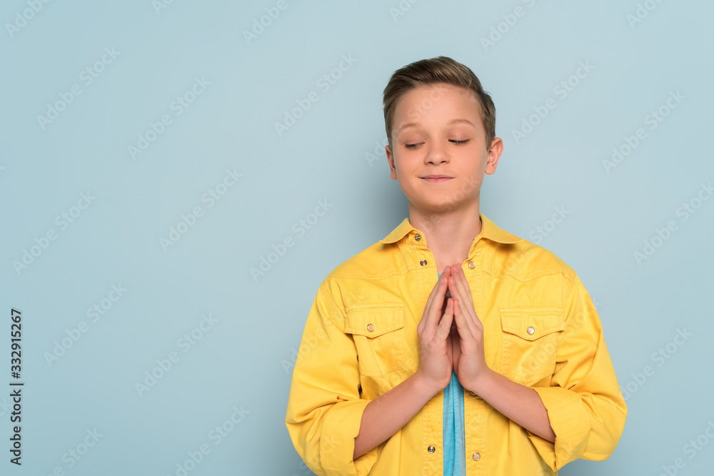 smiling and cute kid showing praying hands on blue background Stock ...