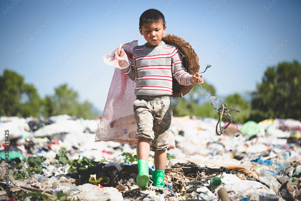 A poor boy collecting garbage waste from a landfill site in the ...