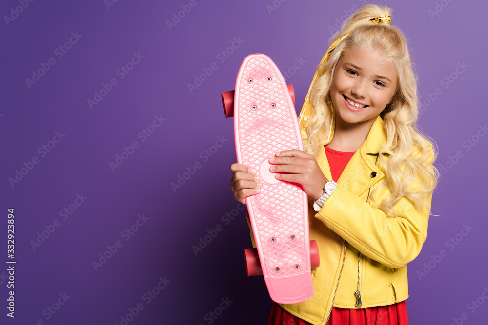 smiling and cute kid holding penny board on purple background Stock ...