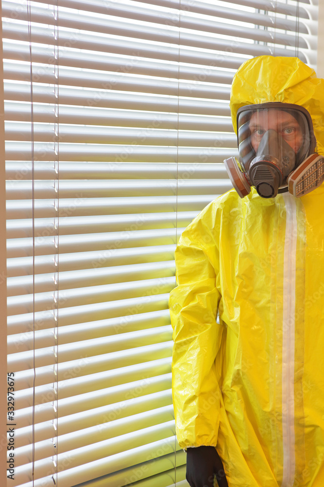 Quarantine - man in professional mask and uniform standing at window ...