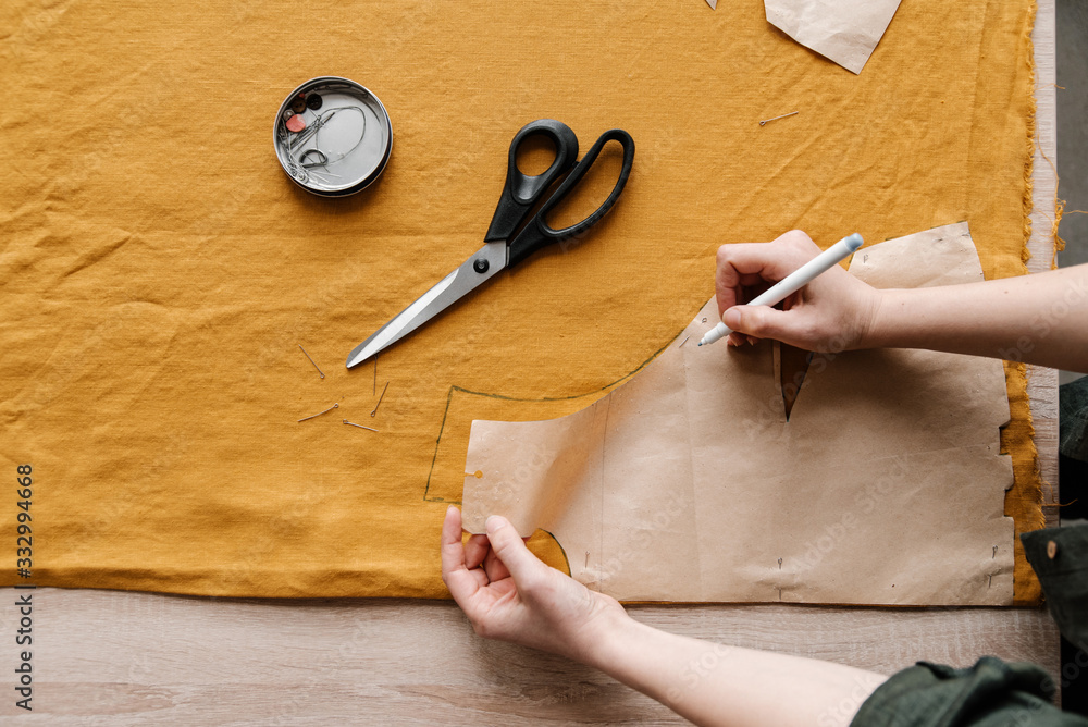 Female Tailor drawing by pencil on yellow tissue. Stock Photo | Adobe Stock