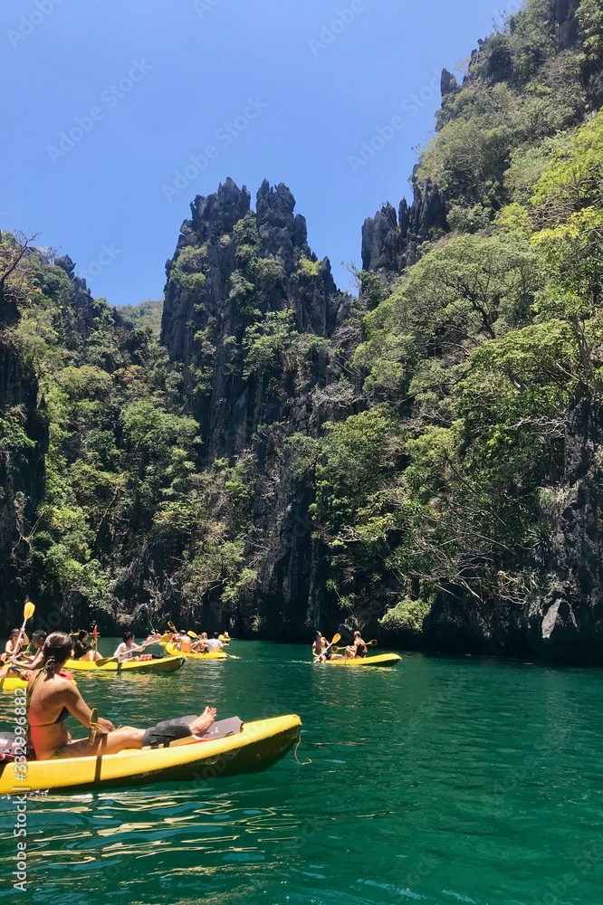 People in kayak in lagoon with green and blue water, with islands in ...