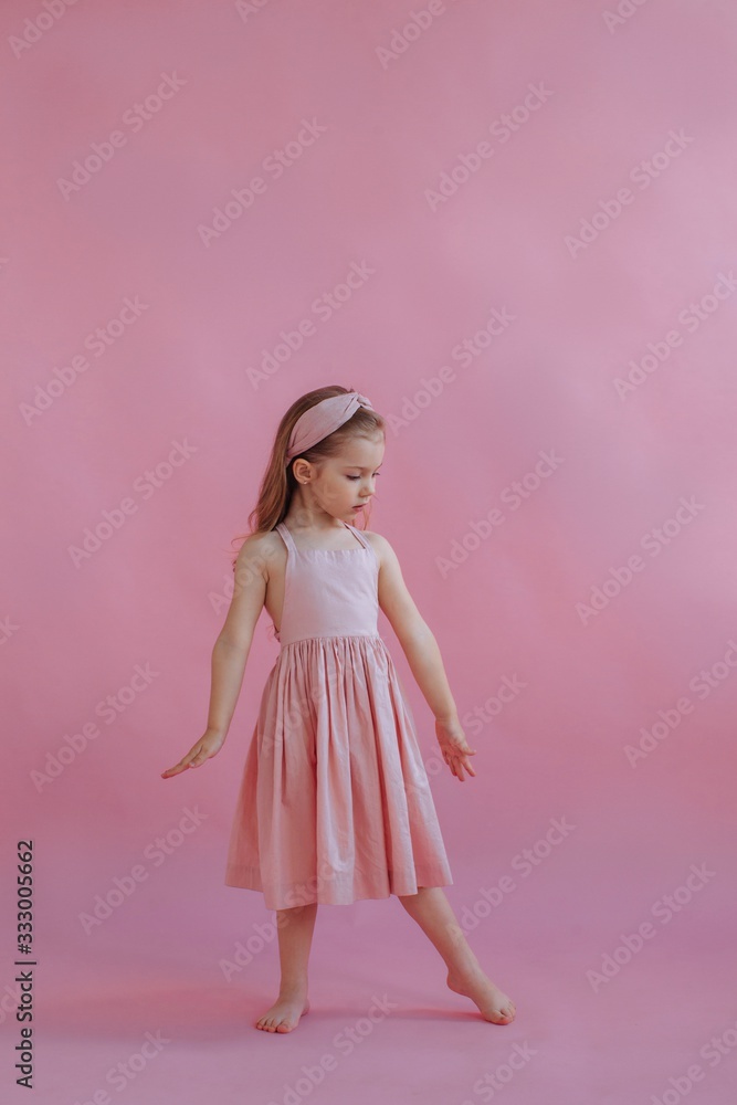 Lovely little girl in pink dress dancing by pink background Stock Photo ...