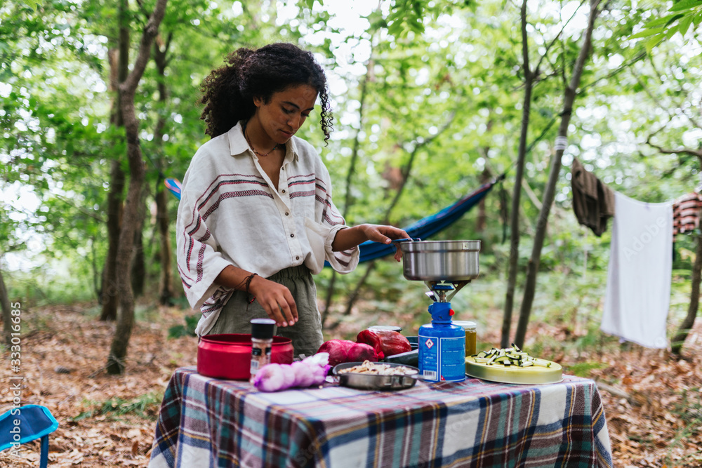 Cooking in the forest. A woman with an amazing curly hair Cooking on a ...
