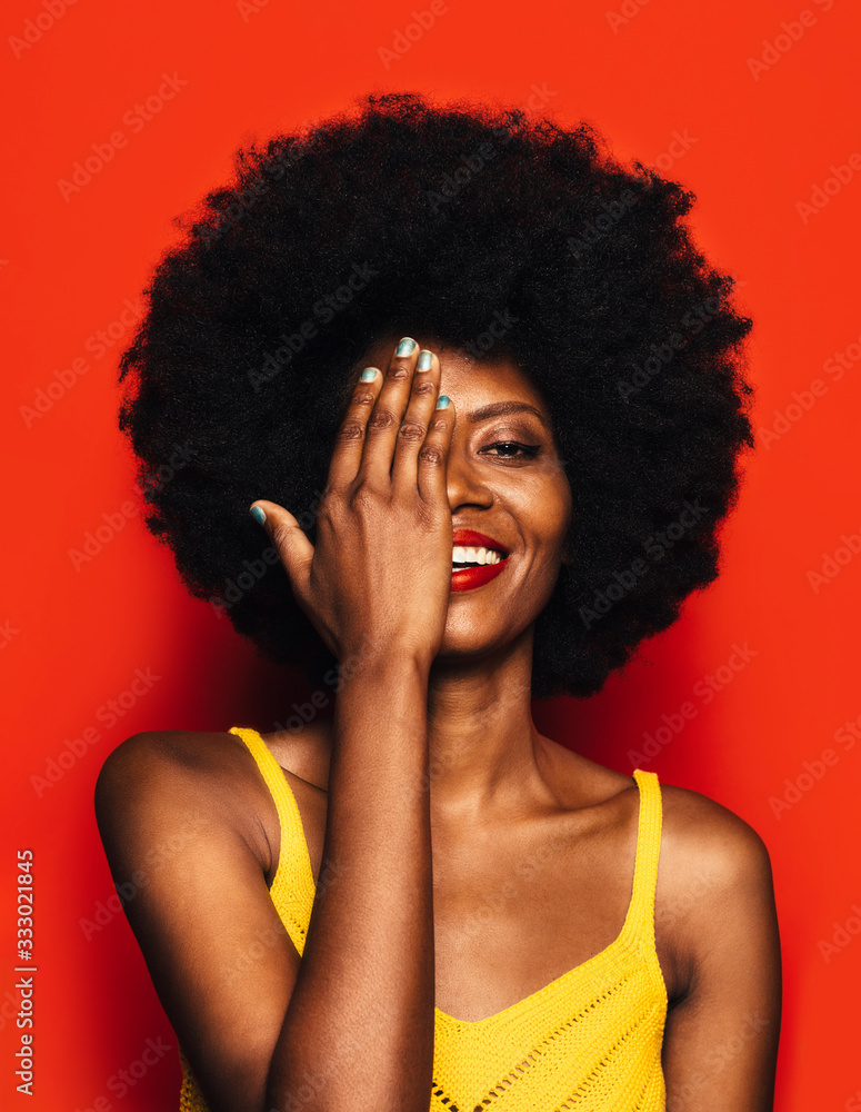 Beautiful Afro Woman posing over red background covering her face with ...