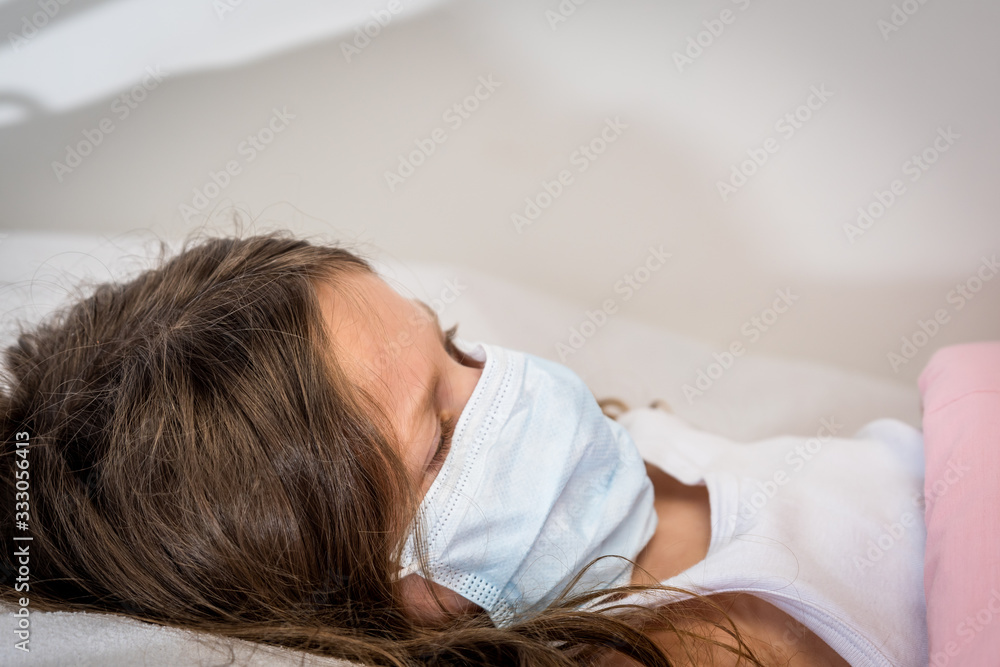 cute little girl using a medical face mask,she is laying on a hospital ...