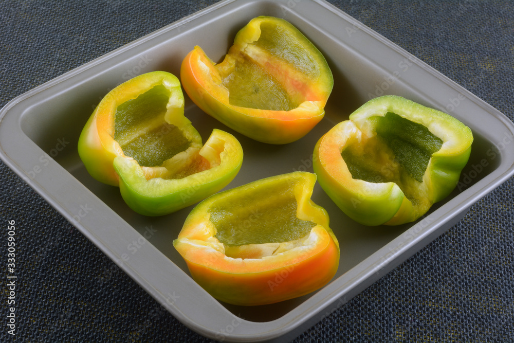 Fresh raw bell pepper halves with seeds removed in nonstick baking pan ...