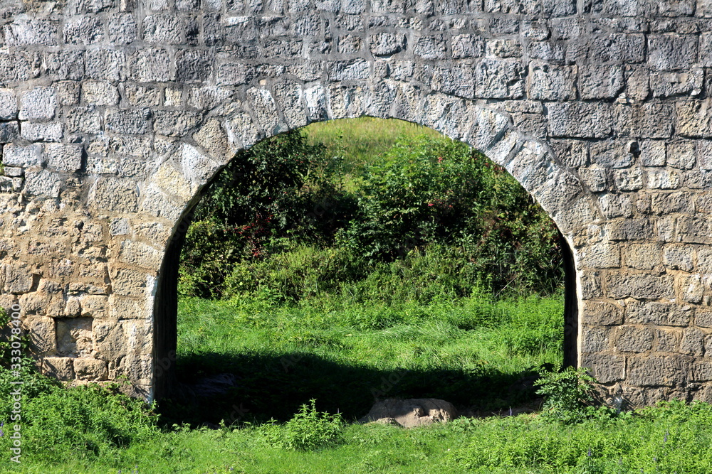 Massive old stone arch under stone bridge allowing access to local ...