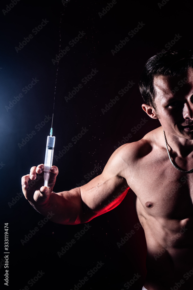 Bodybuilder holding big syringe with injection. concept of steroid in ...