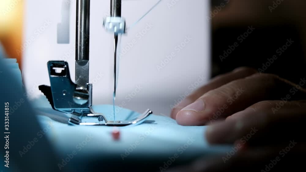 Sewing machine needle rapidly move with tailor woman push light blue ...