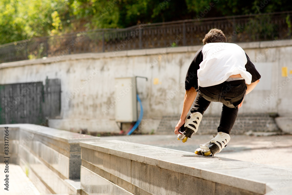 Back view of young professional skater doing stunts outside. Urban ...