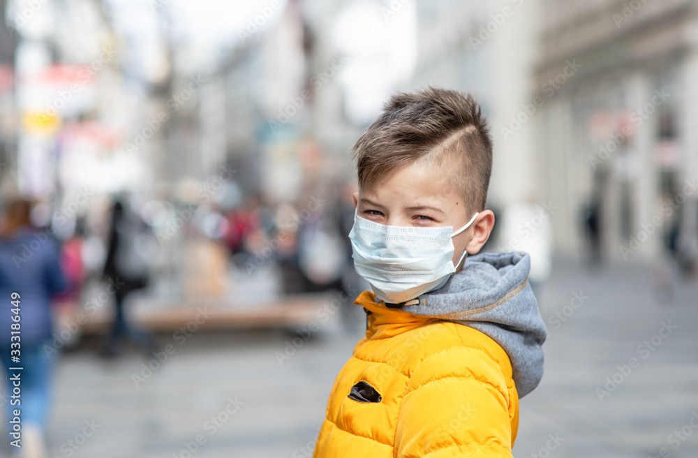 Child boy walking outdoors with face mask protection. School boy ...