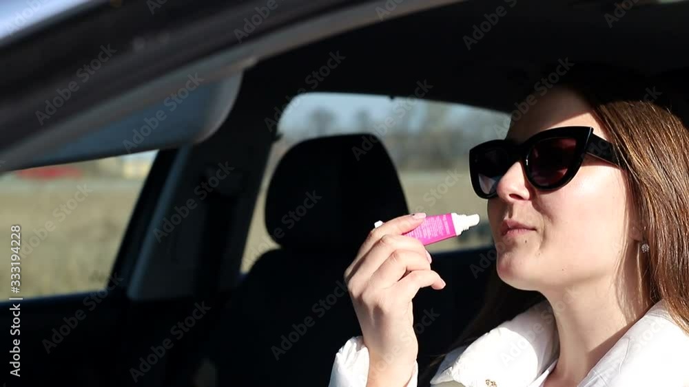 Young woman draws lips in car, draw the outline lips with a pencil at ...