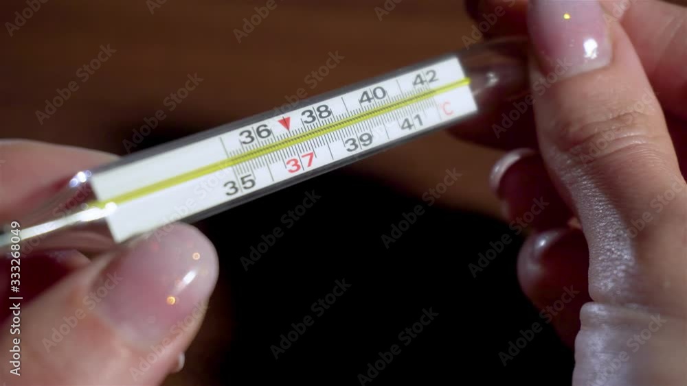 Woman holds thermometer that shows temperature of healthy person in ...