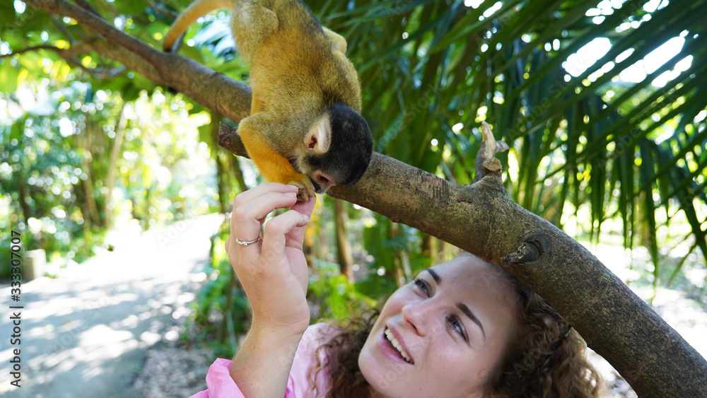 Beautiful curly girl in pink clothes laughs, smiles with saimiri monkey ...