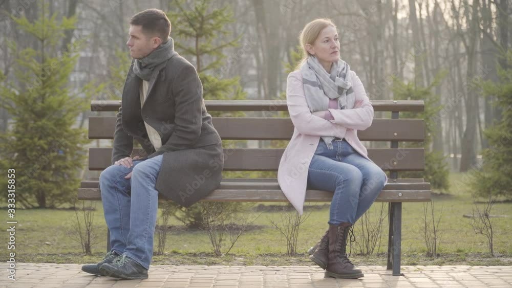 Angry Caucasian man and woman sitting back to back on opposite sides of ...