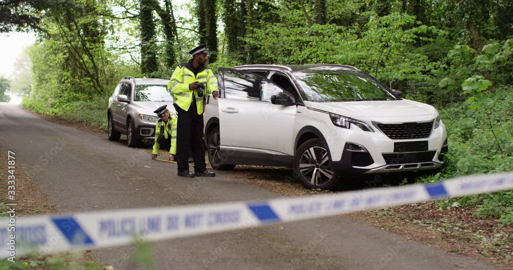 4K Policeman taking photos of a car at crime scene cordoned off with ...
