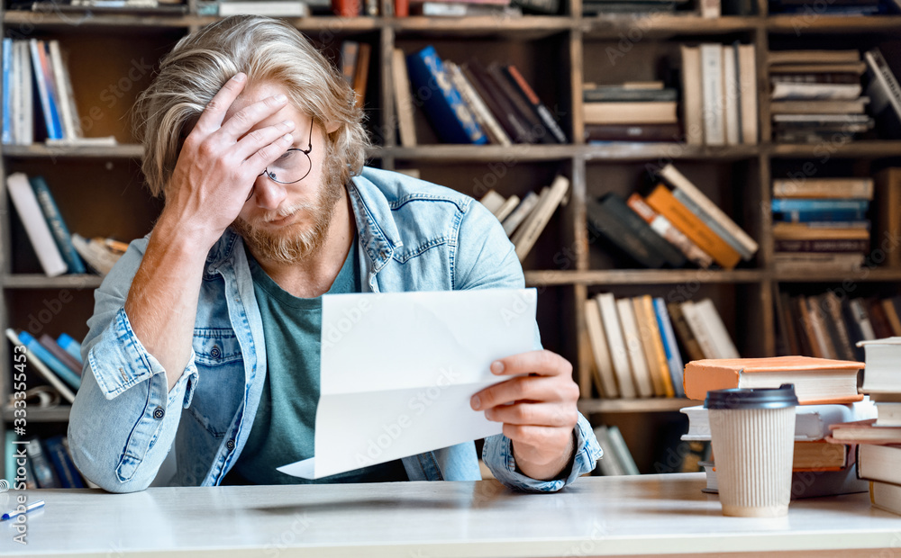 Frustrated depressed desperate young man businessman desk read letter ...