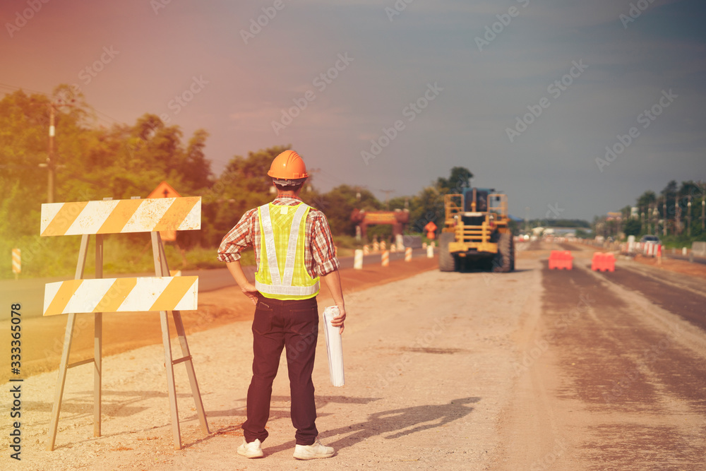Engineer wear a hard helmet and holding blueprint on road construction ...