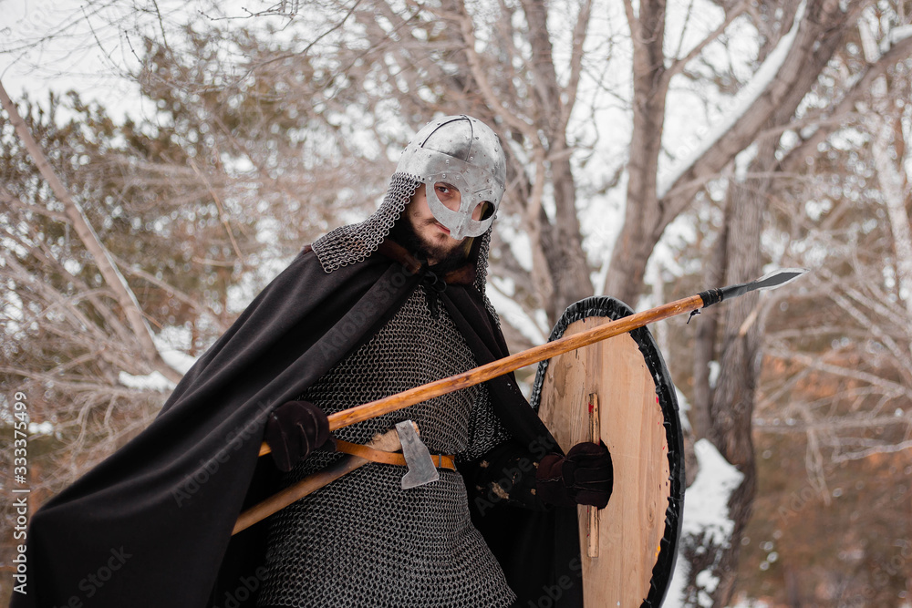 Viking in winter with a spear and a round shield of red-black color. A ...