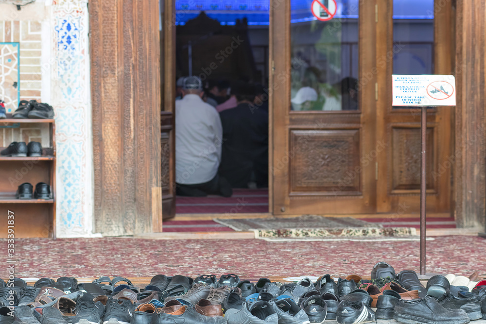 Shoes of praying people and praying people. Bolo Hauz Mosque. Bukhara ...