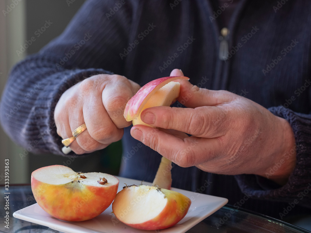 Old man hands peeling organic red Pink Lady apple outside over a bowl ...
