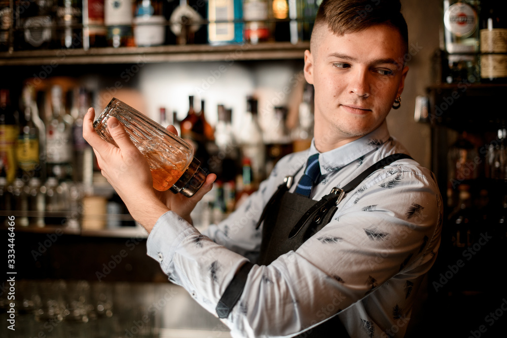 Young handsome bartender standing behind the bar counter with glassy ...