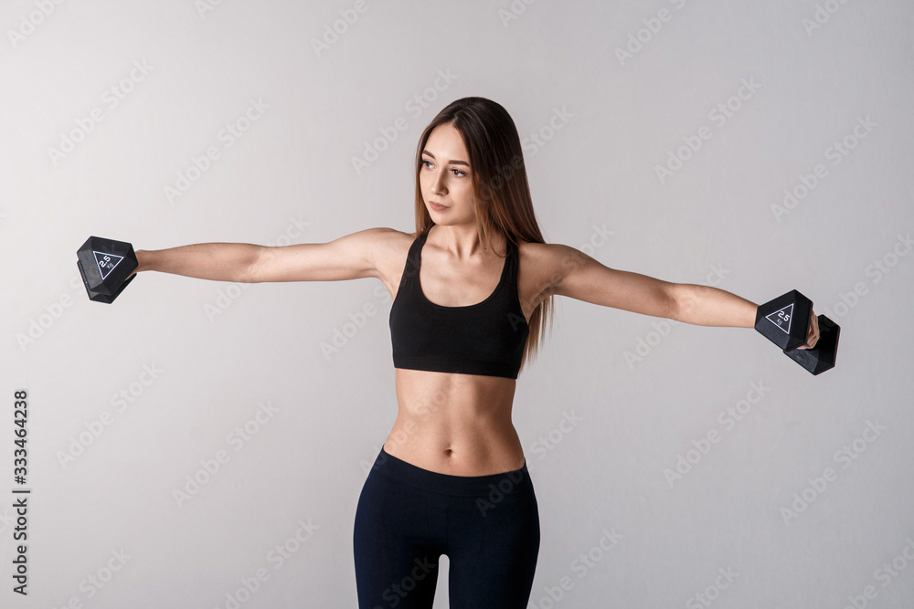 Strong muscular girl working out with dumbbells. Photo of attractive ...