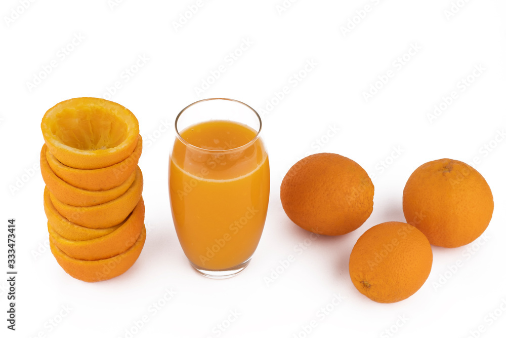 Squeezed oranges' peels and a glass of orange juice on white background ...