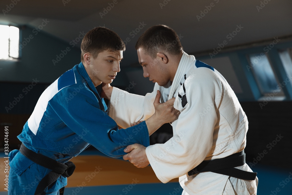 Two young judo caucasian fighters in white and blue kimono with black ...