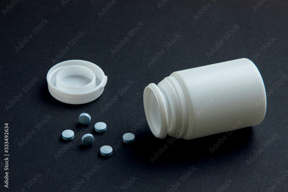 Bote de pastillas destapado con medicamento fuera y fondo negro Stock ...