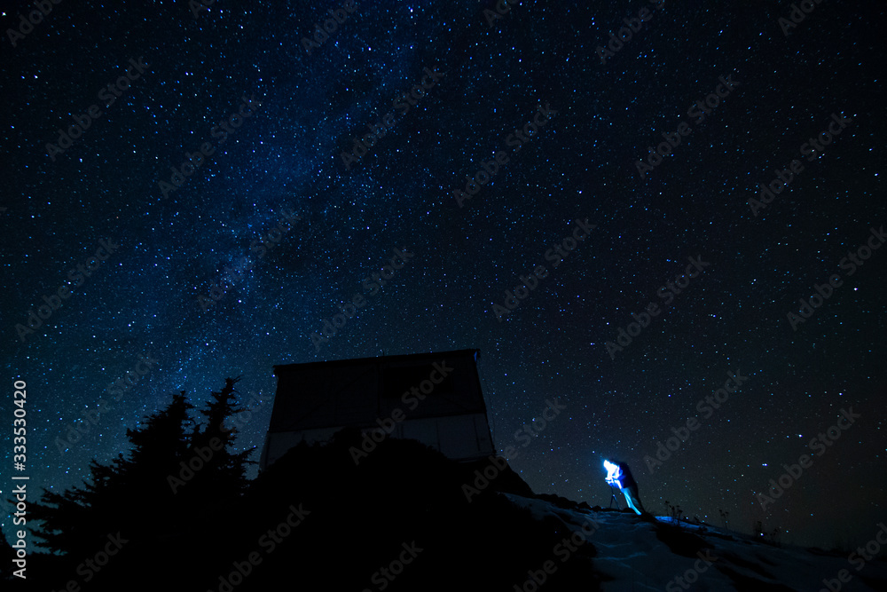 Adventurous man taking photos of the night sky at a fire lookout in ...