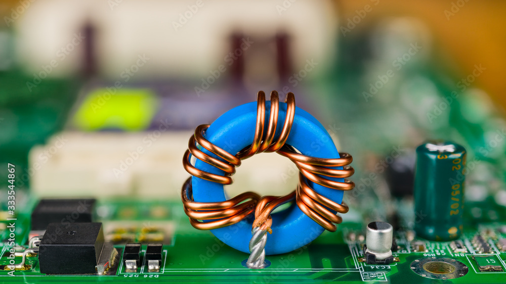 Blue toroidal induction coil on green circuit board. Computer mainboard ...