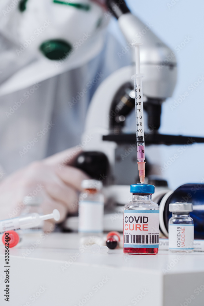 Microbiologist examines the sample under a microscope. Coronavirus ...