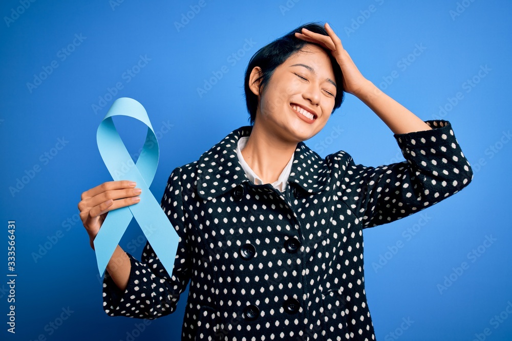 Young beautiful asian girl holding blue cancer ribbon symbol over ...