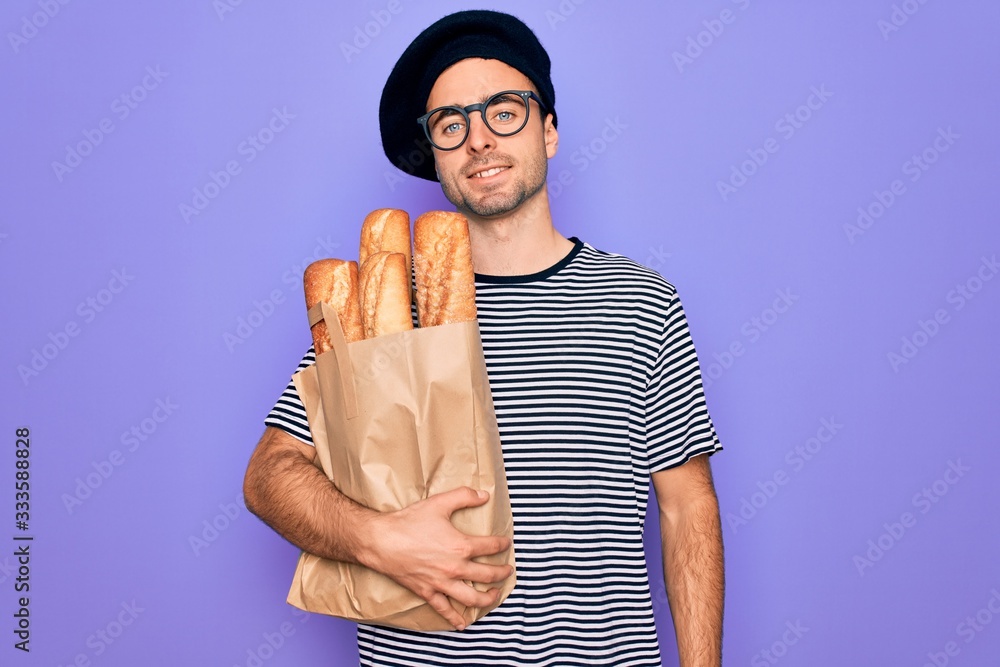 Young handsome baker man with blue eyes wearing french beret holding ...