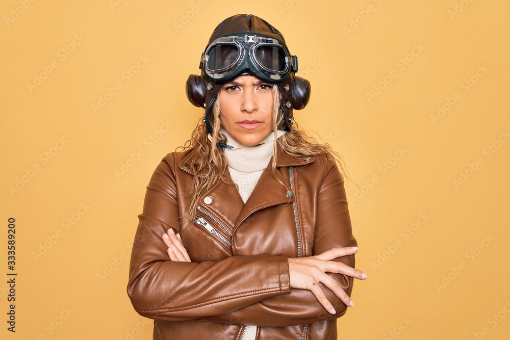 Young beautiful blonde aviator woman wearing vintage pilot helmet whit ...