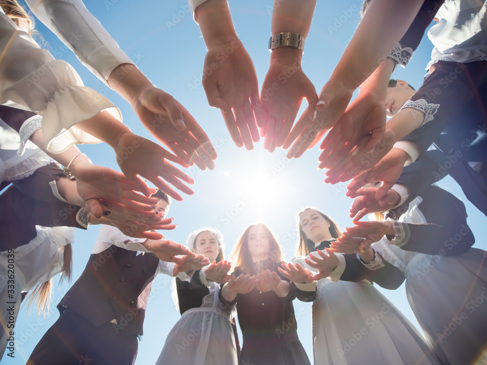 Students graduates make the shape of a circle from the palms of their ...