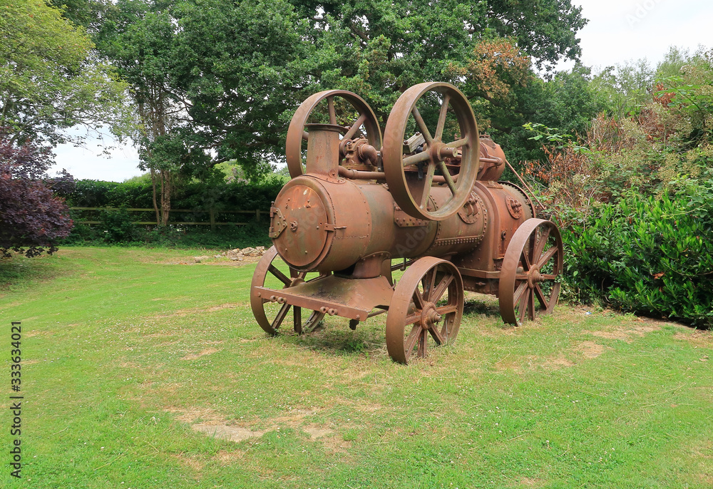 A landscape scene with green trees and grass with an old traction ...