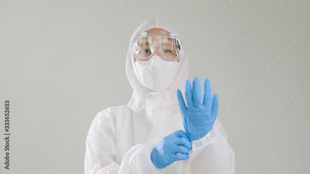 Asian doctor in protective hazmat PPE suit wearing medical latex gloves ...
