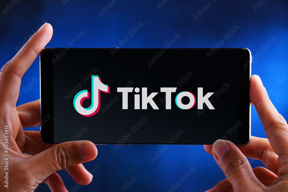 Hands holding smartphone displaying logo of TikTok Stock Photo | Adobe ...