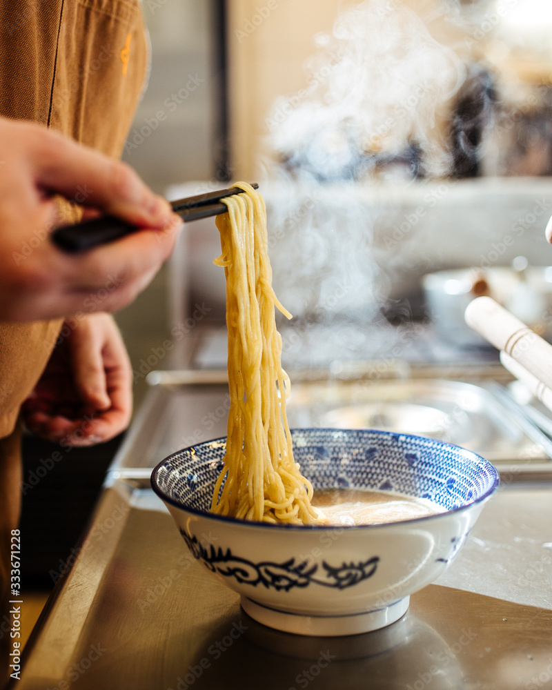 Chef cooking ramen noodles in the restaurant kitchen, side view ...