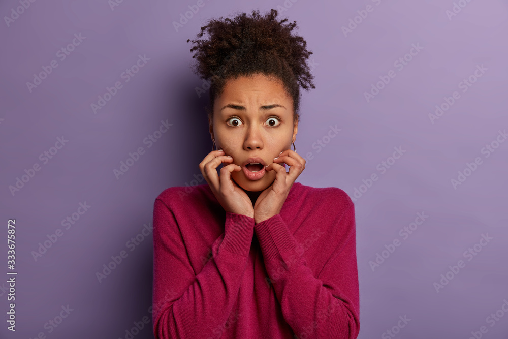 Frightened concerned woman feels worried, trembles from fear, watches ...