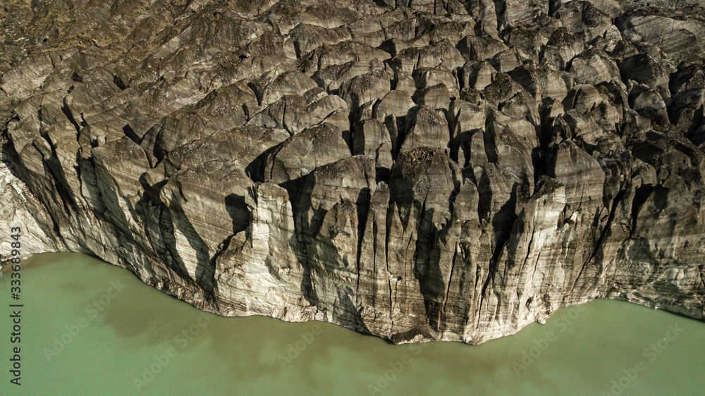 Aerial sideview on Black Glaciar covered with volcanic black ash. Black ...